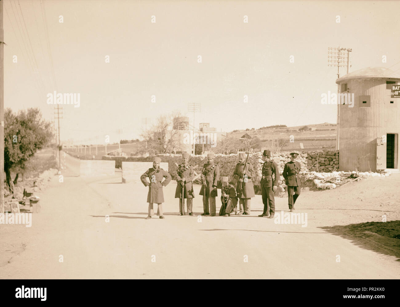 Police and guards in road next to a concrete guard tower with sign ...