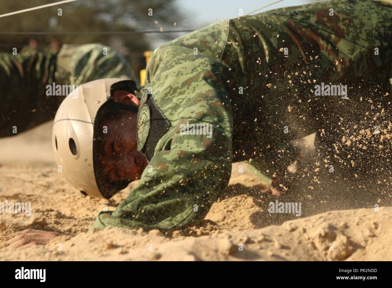 A Mexican competitior crawls through sand as part of the grueling ...