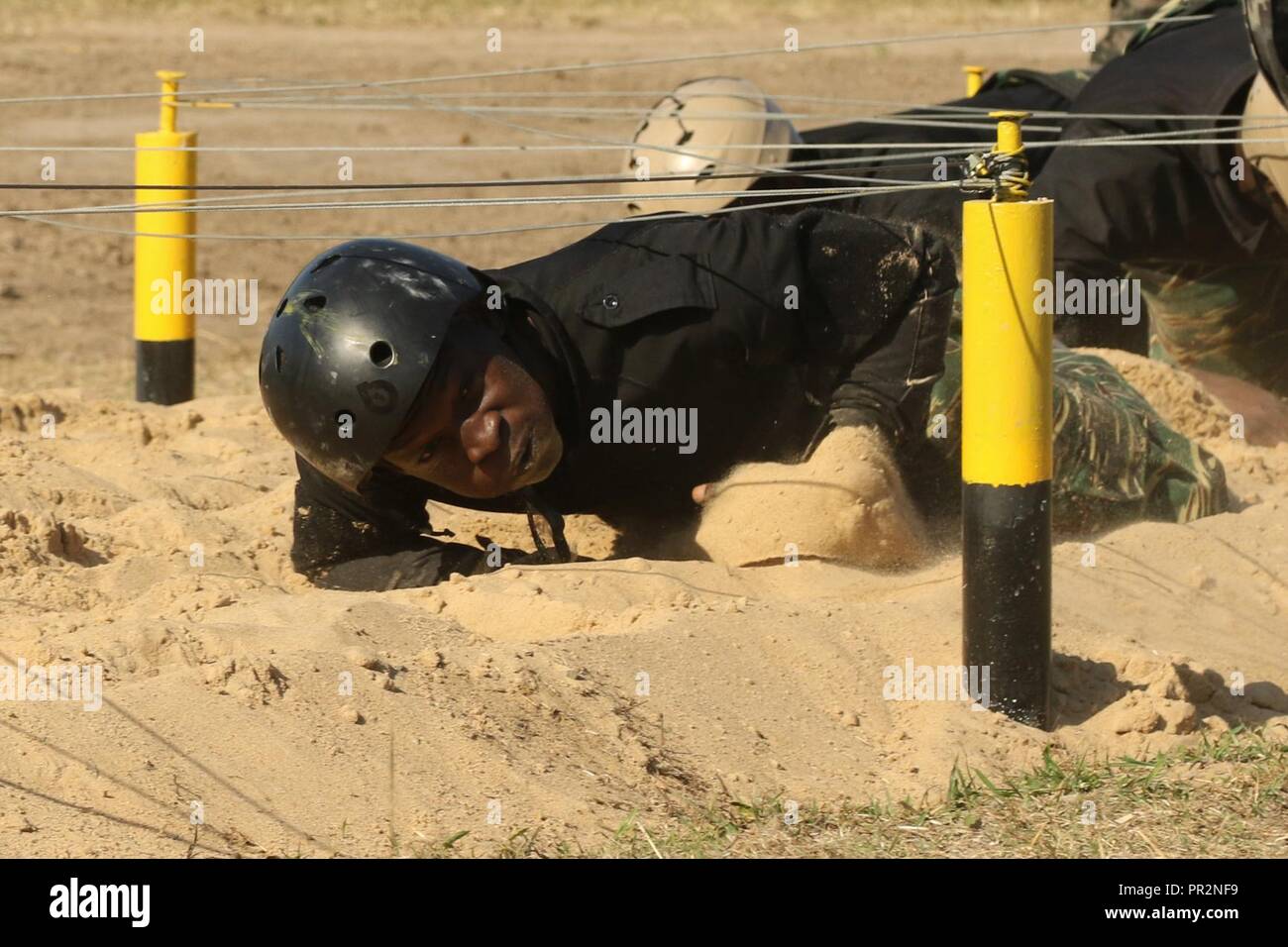 A Guyanese comando crawls beneath wires during a Fuerzas Comando ...