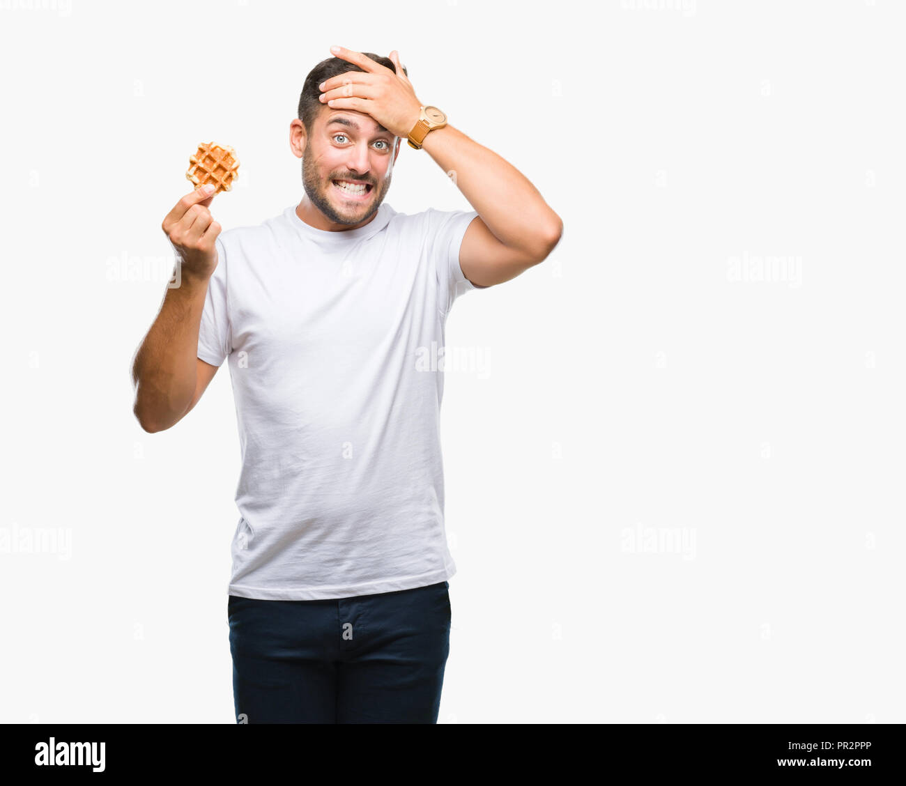 Young handsome man eating a sweet waffle over isolated background ...