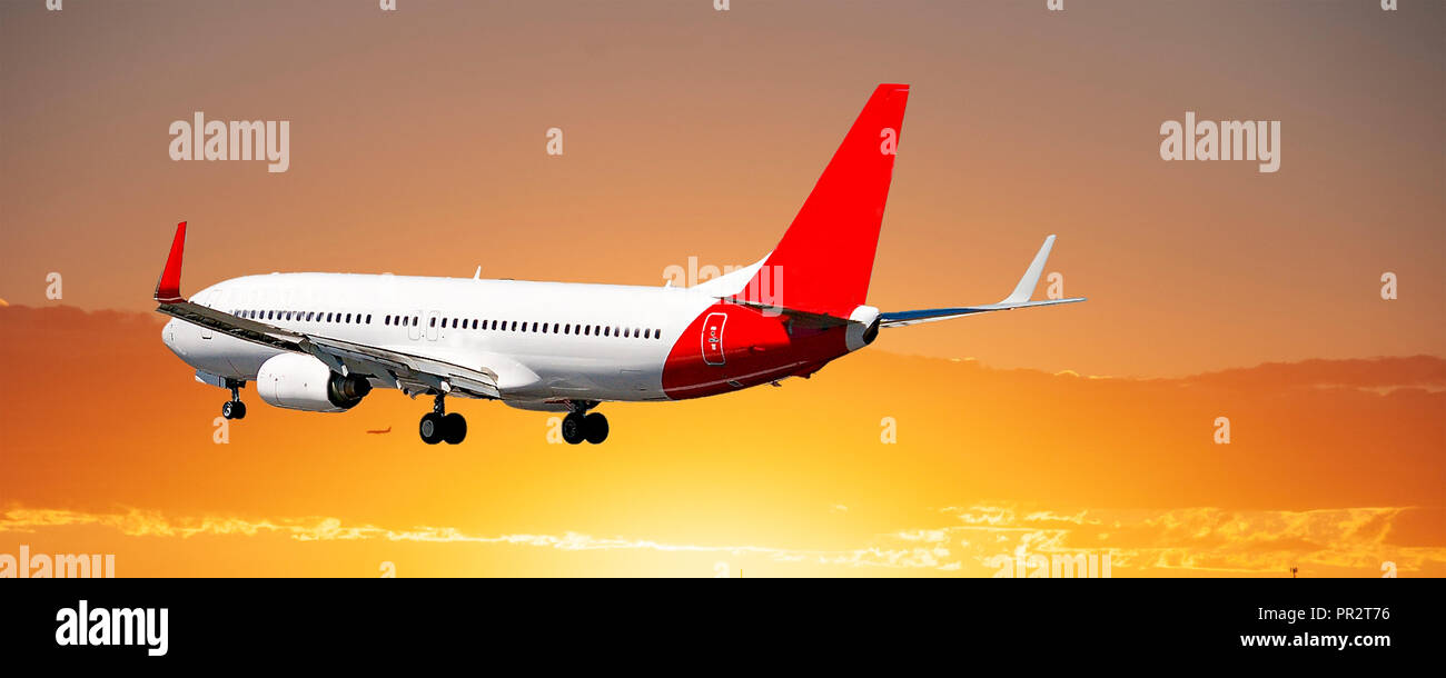 A commercial passenger jet flying closeup in a yellow and orange ...