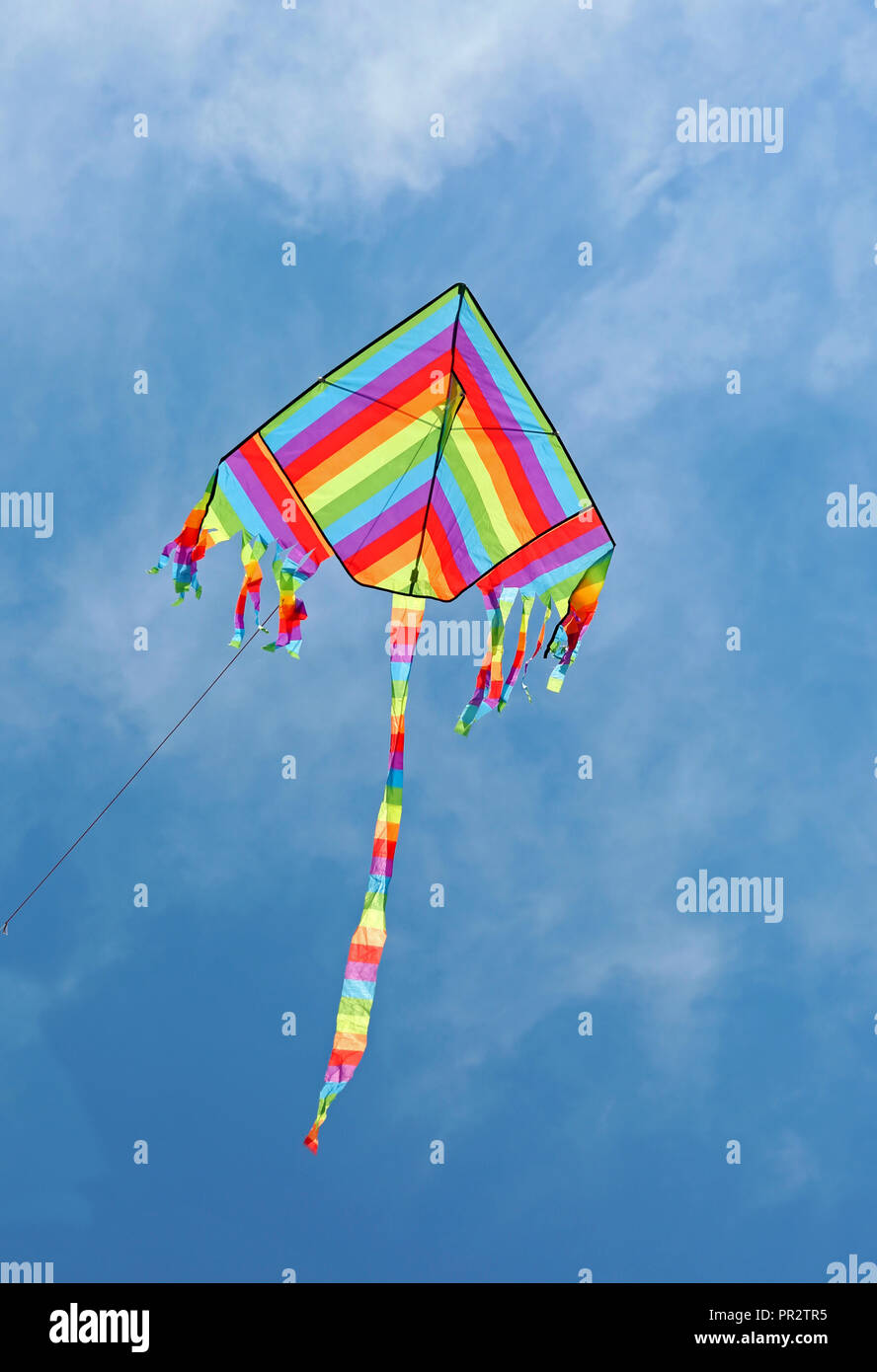 kite with the colors of the rainbow flies high in the blue sky Stock ...