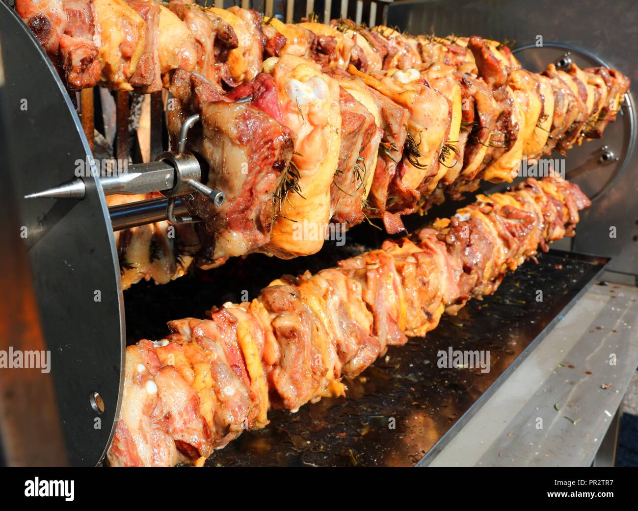 very long Long spit with many skewers filled of chicken and pork meat ...