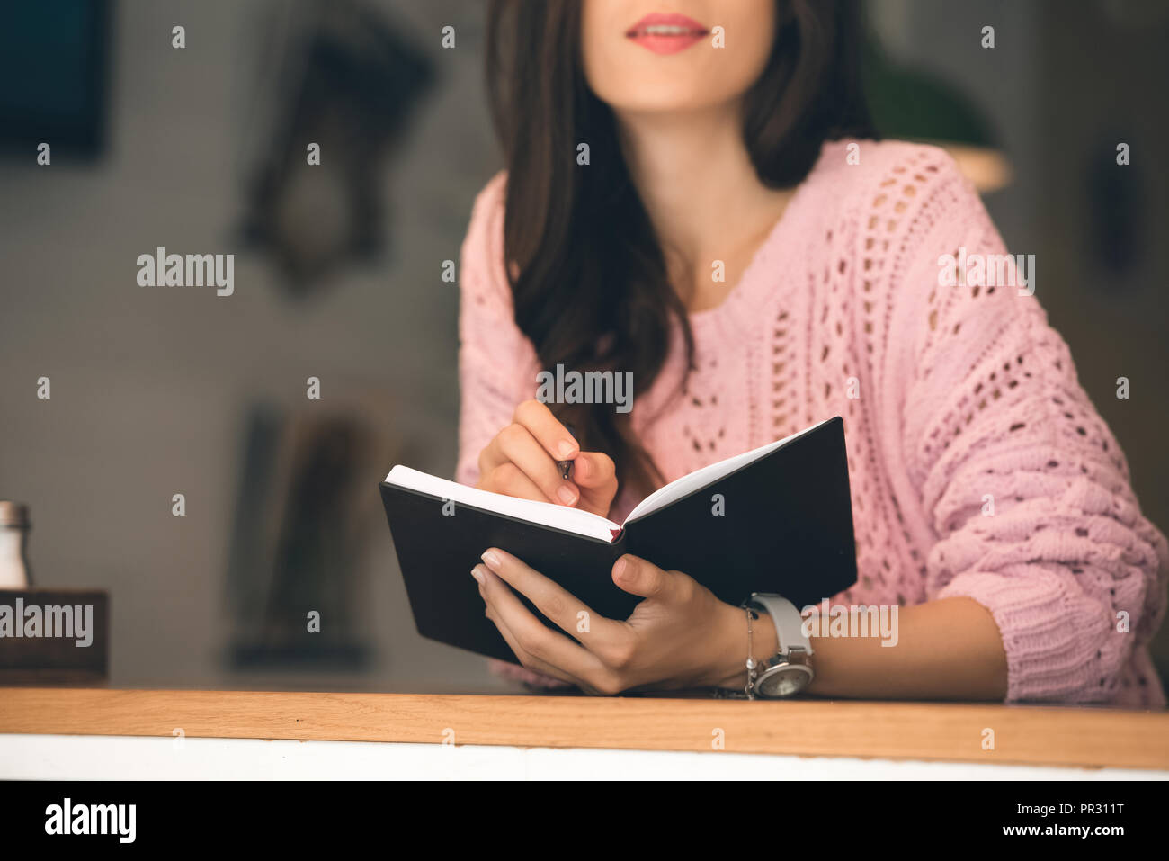 partial view of woman making notes in textbook at table in cafe Stock ...