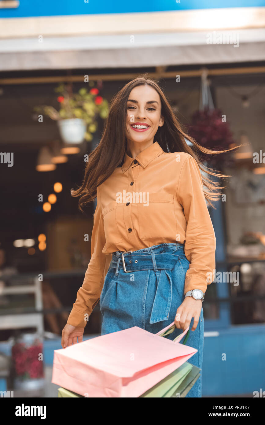 young happy stylish female shopper walking with shopping bags at city ...