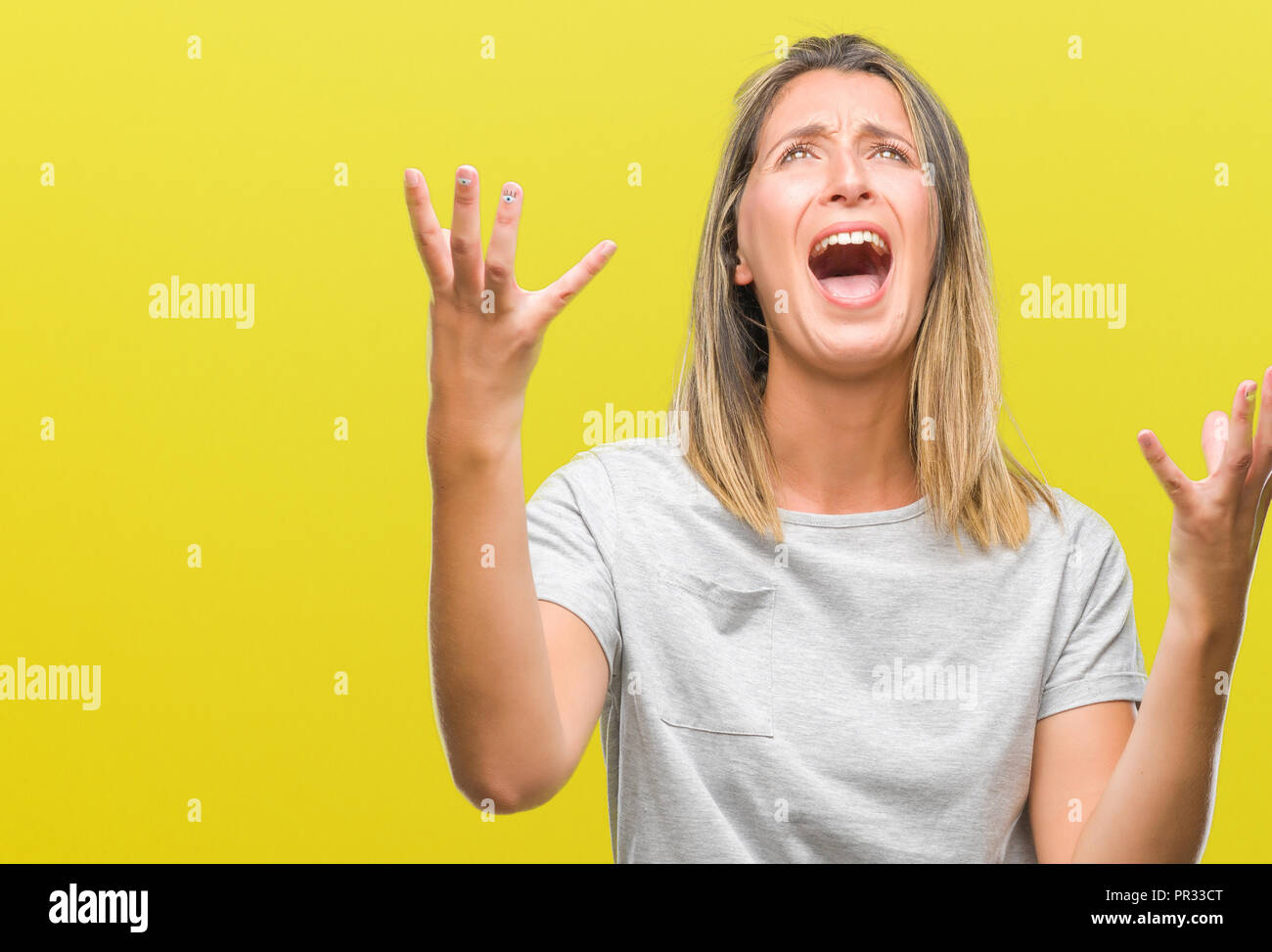 Young beautiful woman over isolated background crazy and mad shouting ...