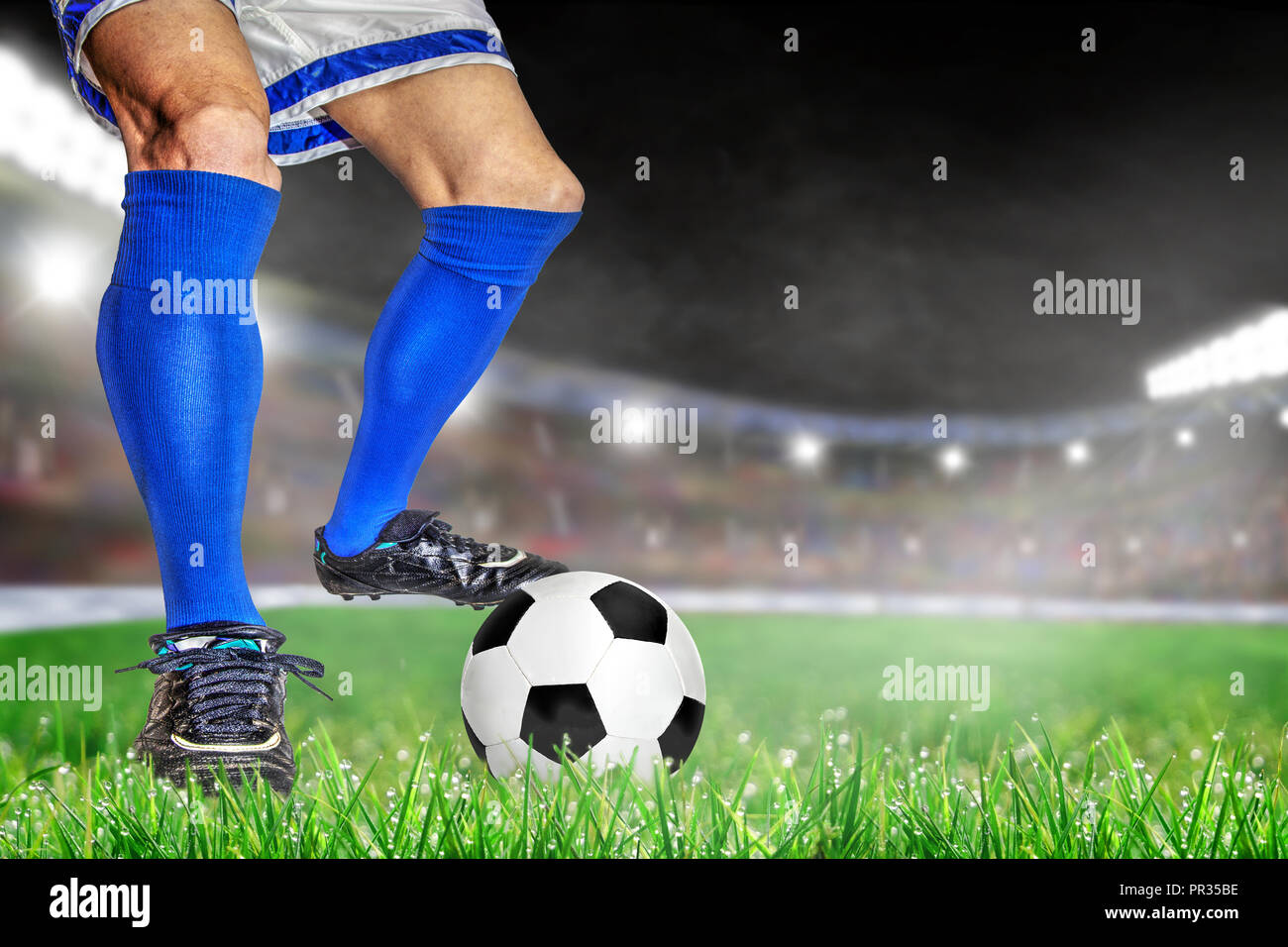 Soccer player in action with football in brightly lit outdoor stadium ...