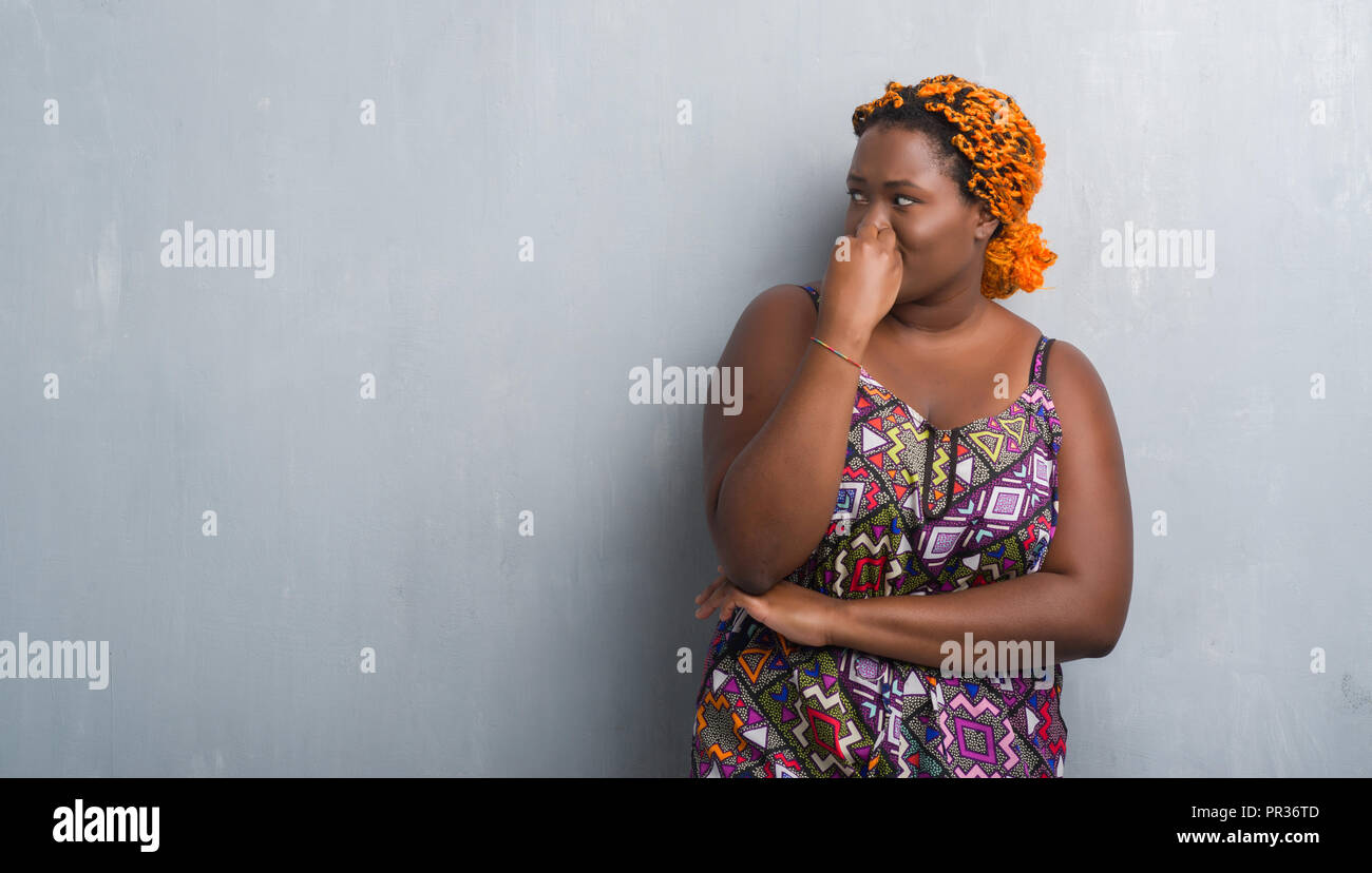 Young african american woman over grey grunge wall wearing orange ...