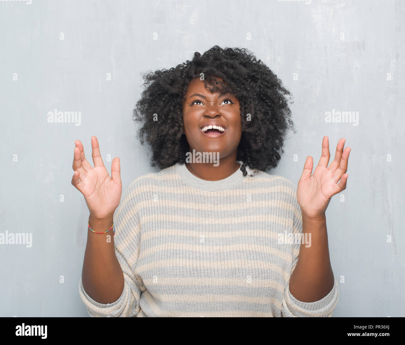 Young african american plus size woman over grey grunge wall wearing a ...