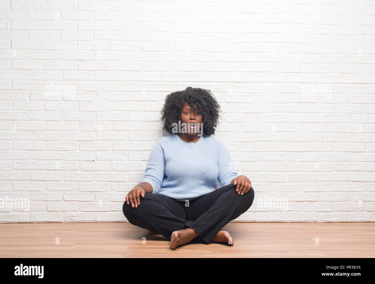 Young african american woman sitting on the floor at home afraid and ...