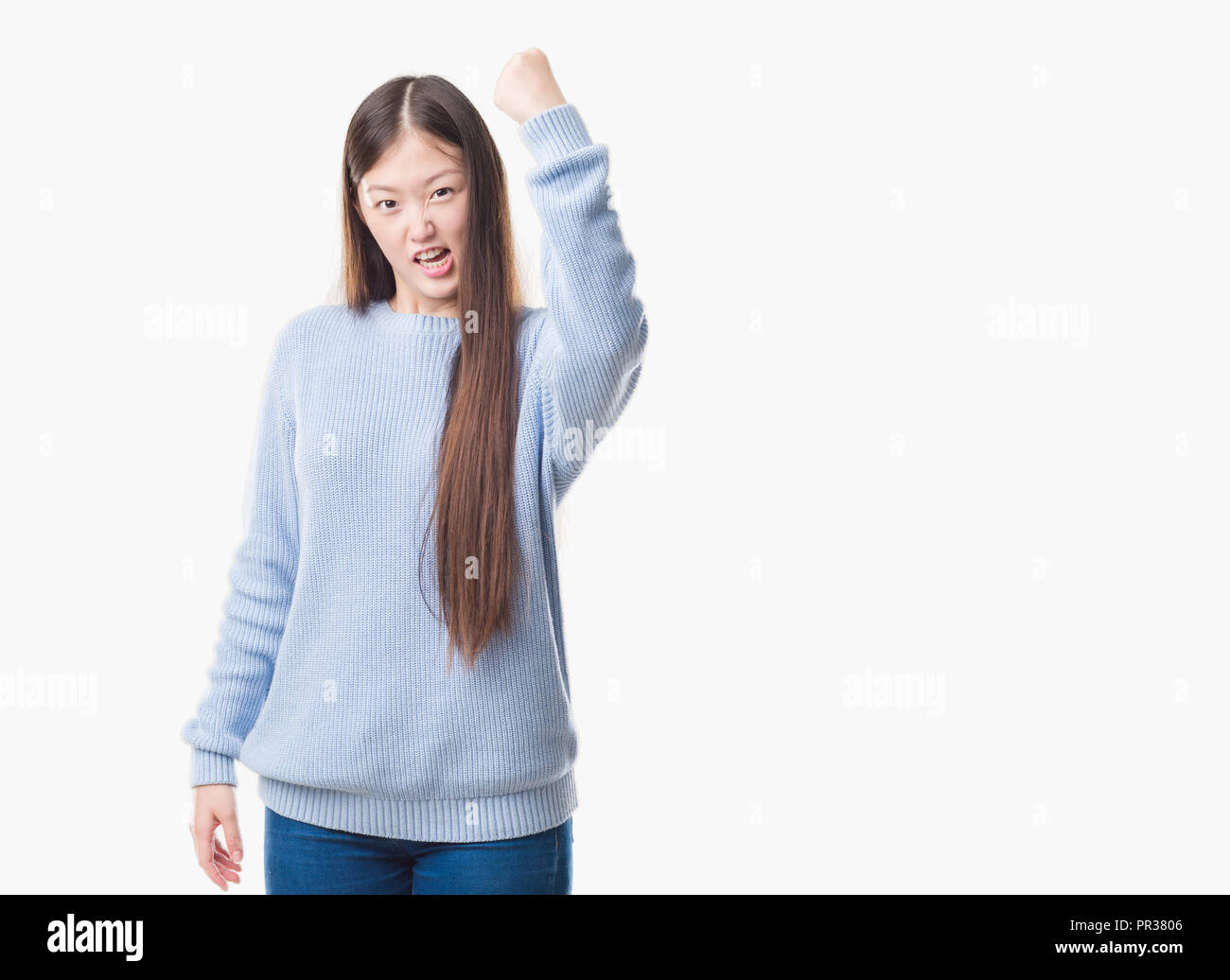 Young Chinese woman over isolated background angry and mad raising fist ...