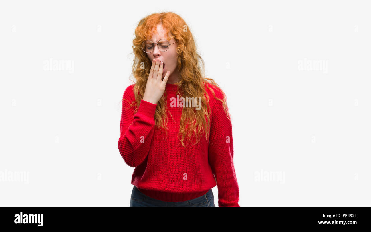 Young redhead woman wearing red sweater bored yawning tired covering ...