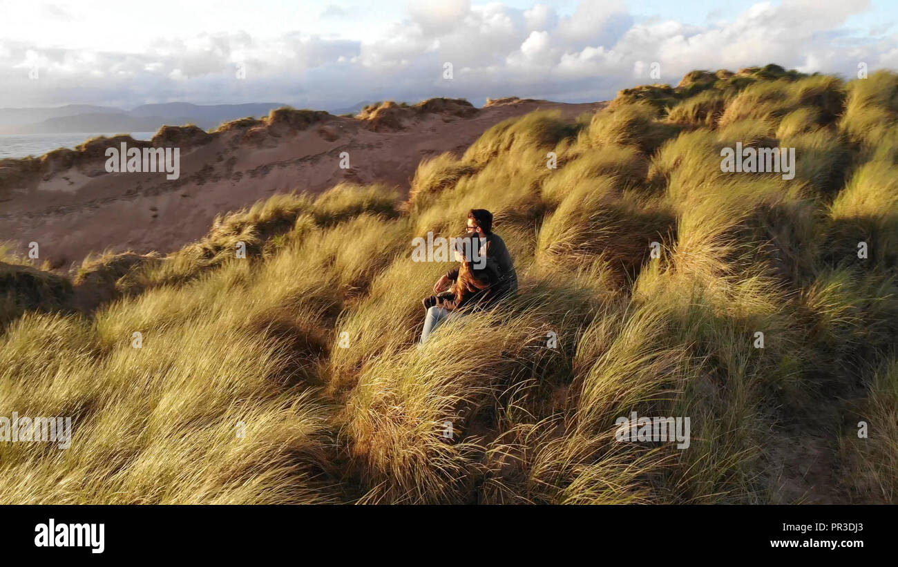 Aerial view over a couple sitting on the dunes at the Irish west coast ...