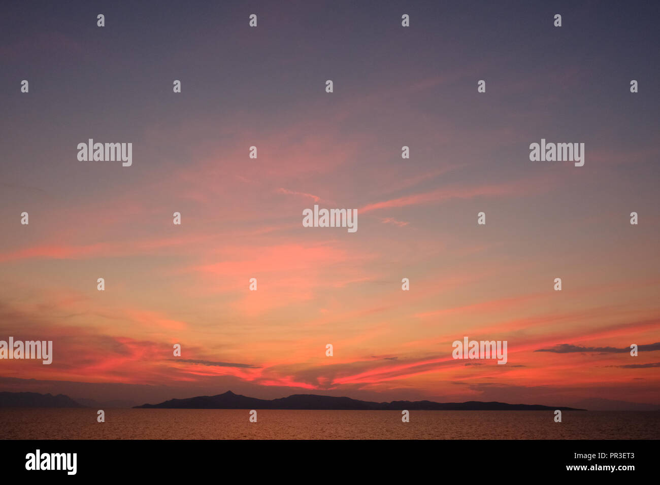 Sunset on the seaside in Greece, red light and few clouds in the sky ...