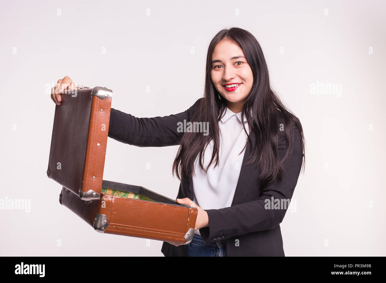 Happy brunette girl wearing formal clothes opening retro suitcase in ...