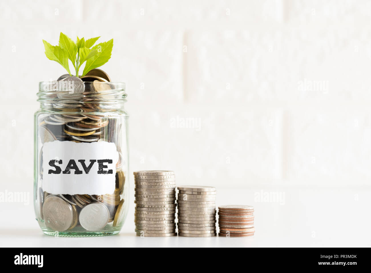 Abstract money saving small young tree with glass jar coins with SAVE ...