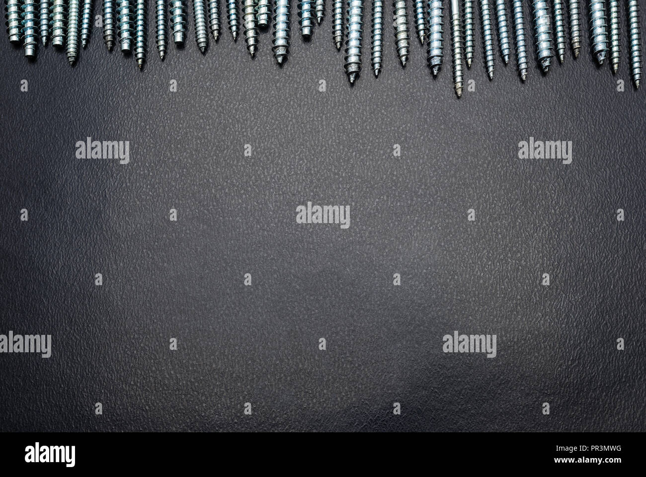 A lot of wood screws, lying on a black, rough table, flat view from ...