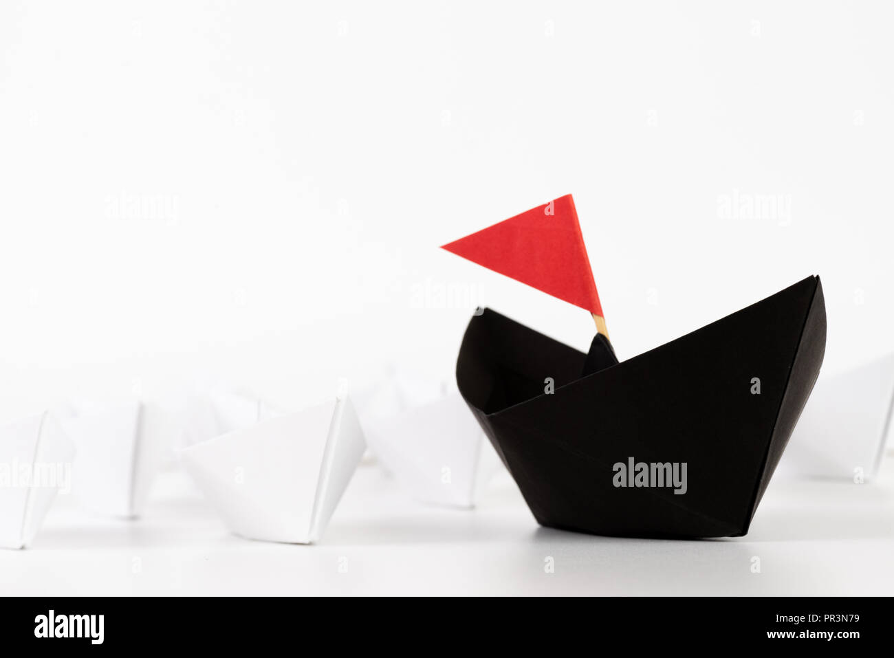 Leadership concept. black paper ship lead among white. One leader ship ...