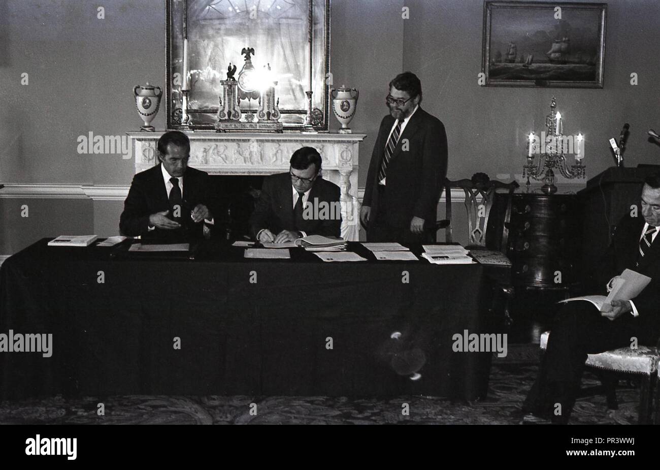 TWO MEN SIGNING SOME PAPERS IN FRONT OF A GROUP OF PEOPLE Stock Photo ...