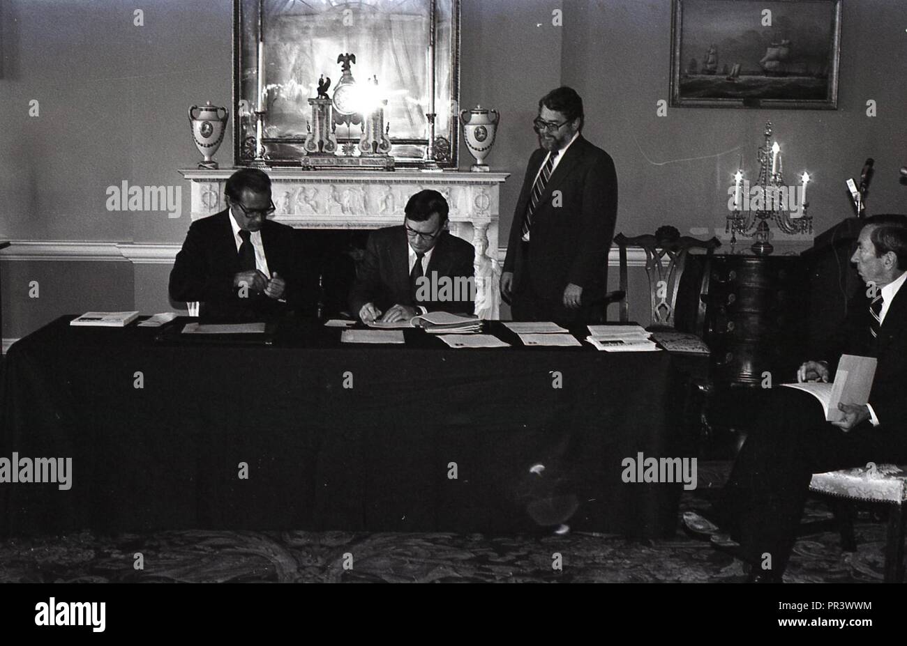 TWO MEN SIGNING SOME PAPERS IN FRONT OF A GROUP OF PEOPLE Stock Photo ...