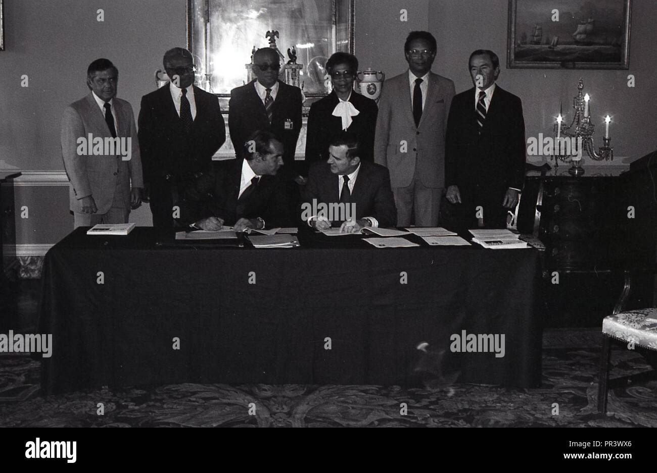 TWO MEN SIGNING SOME PAPERS IN FRONT OF A GROUP OF PEOPLE Stock Photo ...