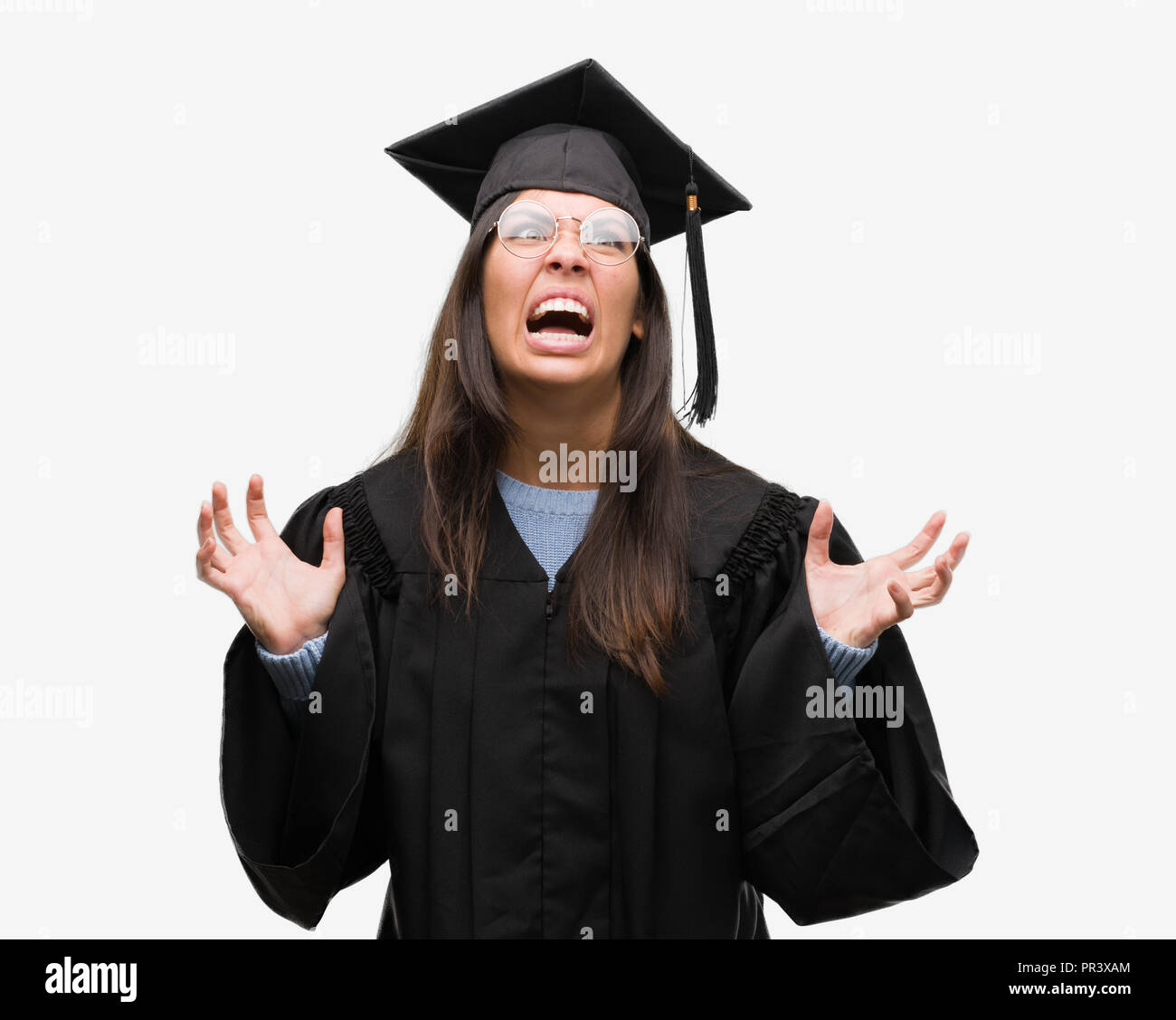 Young hispanic woman wearing graduated cap and uniform crazy and mad ...
