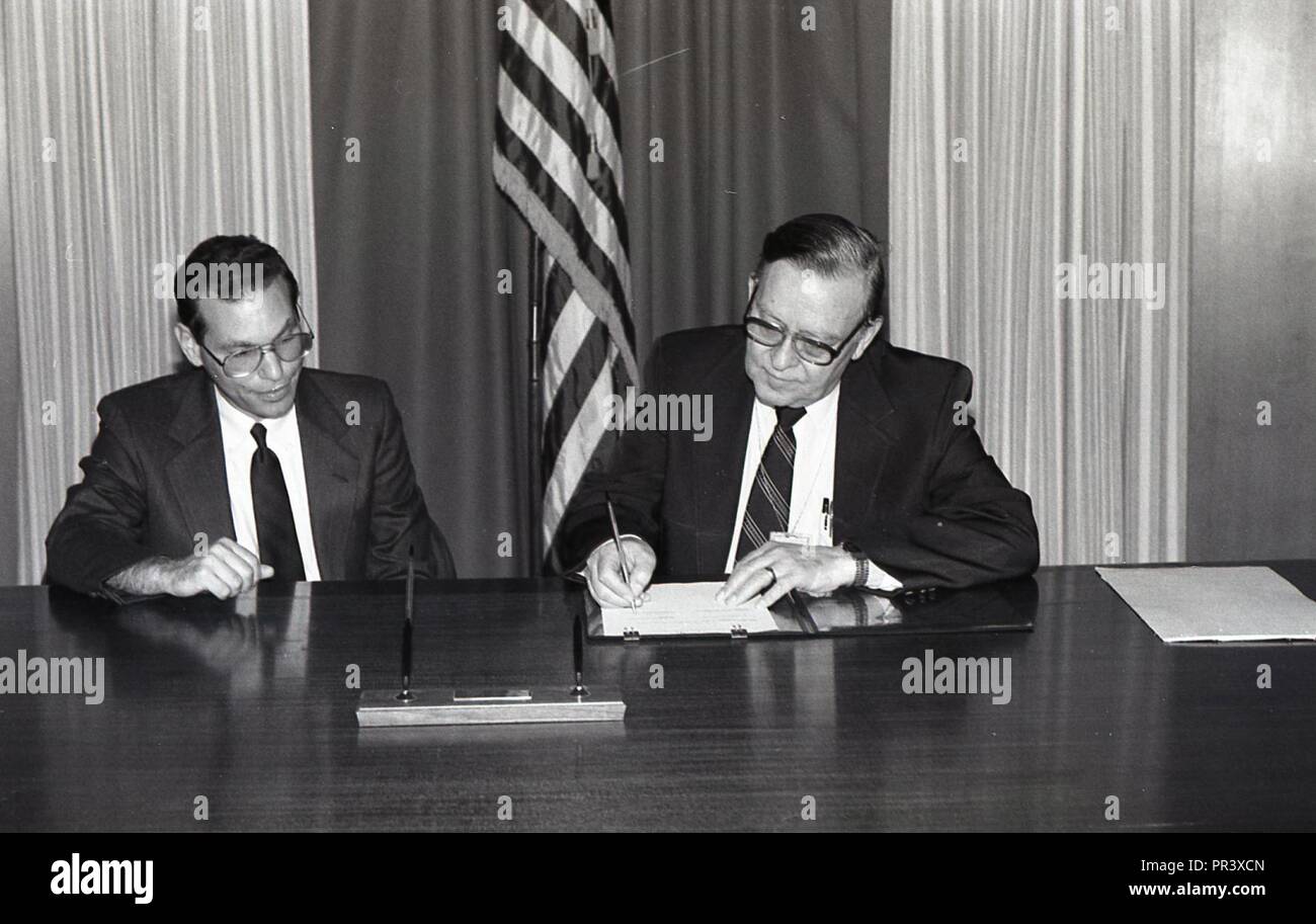 TWO MEN AT THE TABLE WITH ONE OF THE MEN SIGNING SOME PAPERS Stock ...