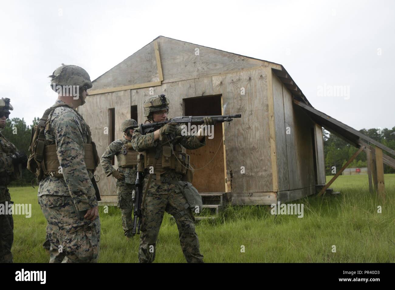 A Marine fires an M500 shotgun at practice targets during urban ...
