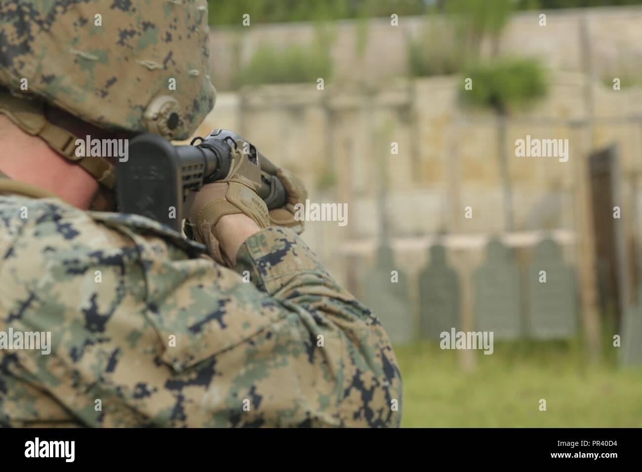 A Marine aims with an M500 shotgun at practice targets during urban ...