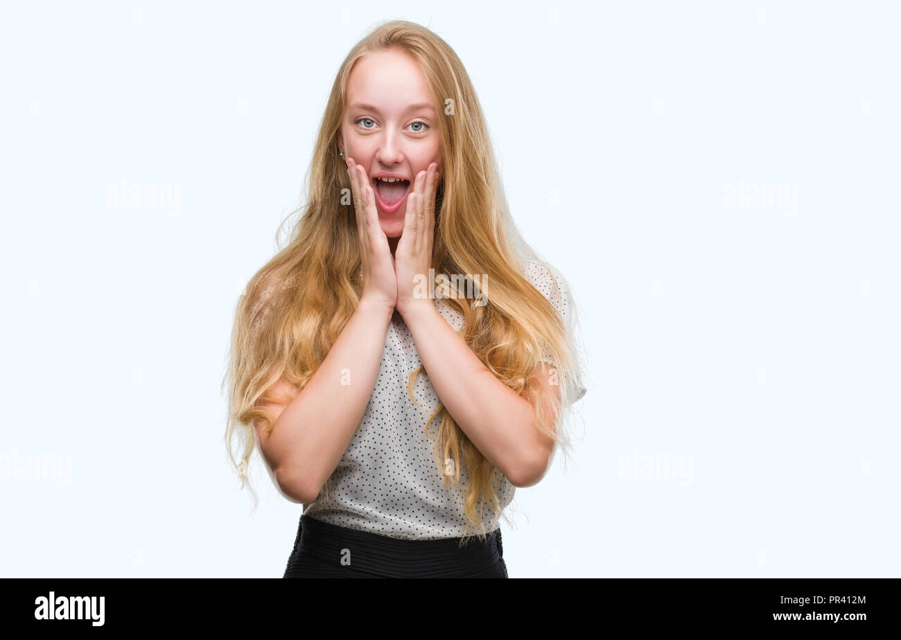 Blonde teenager woman wearing moles shirt afraid and shocked with ...