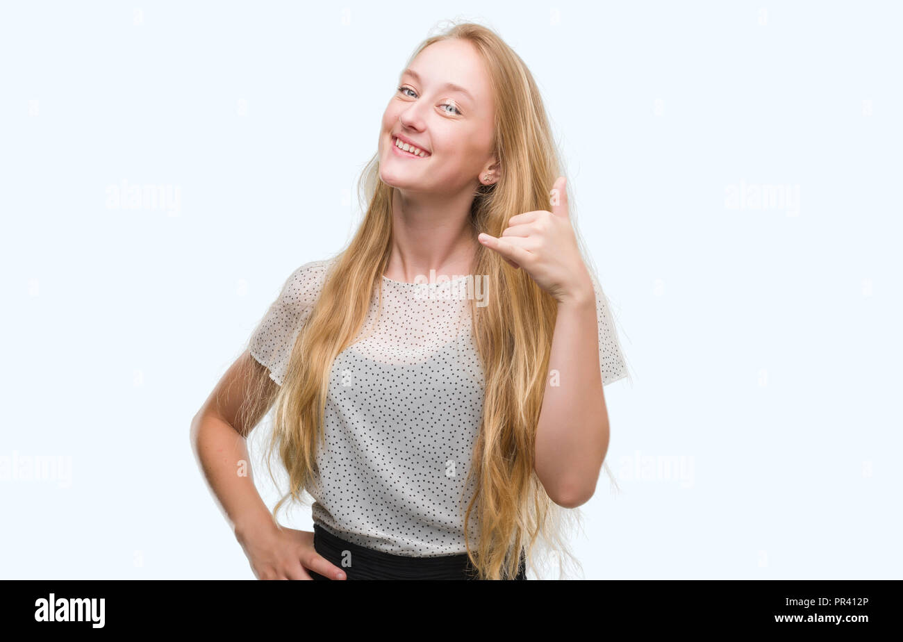 Blonde teenager woman wearing moles shirt smiling doing phone gesture ...