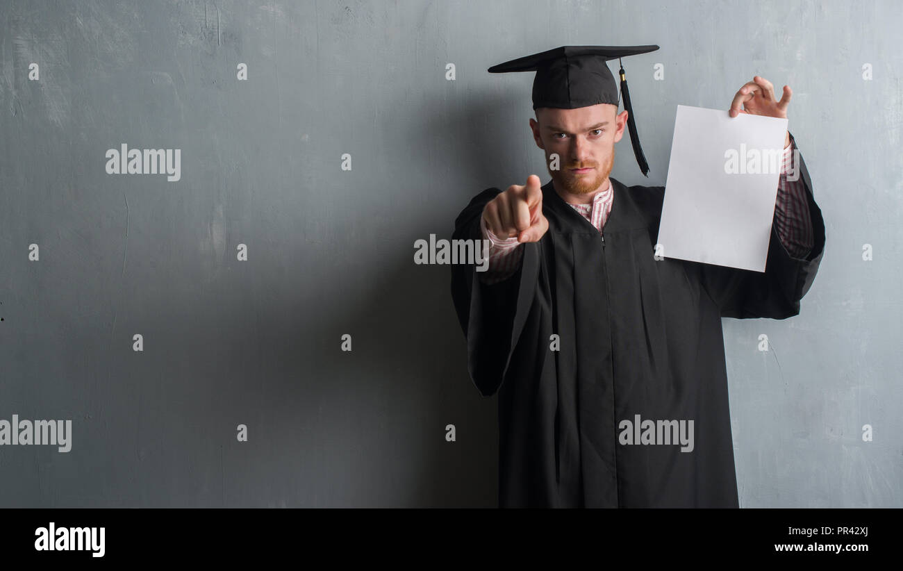 Young redhead man over grey grunge wall wearing graduate uniform ...