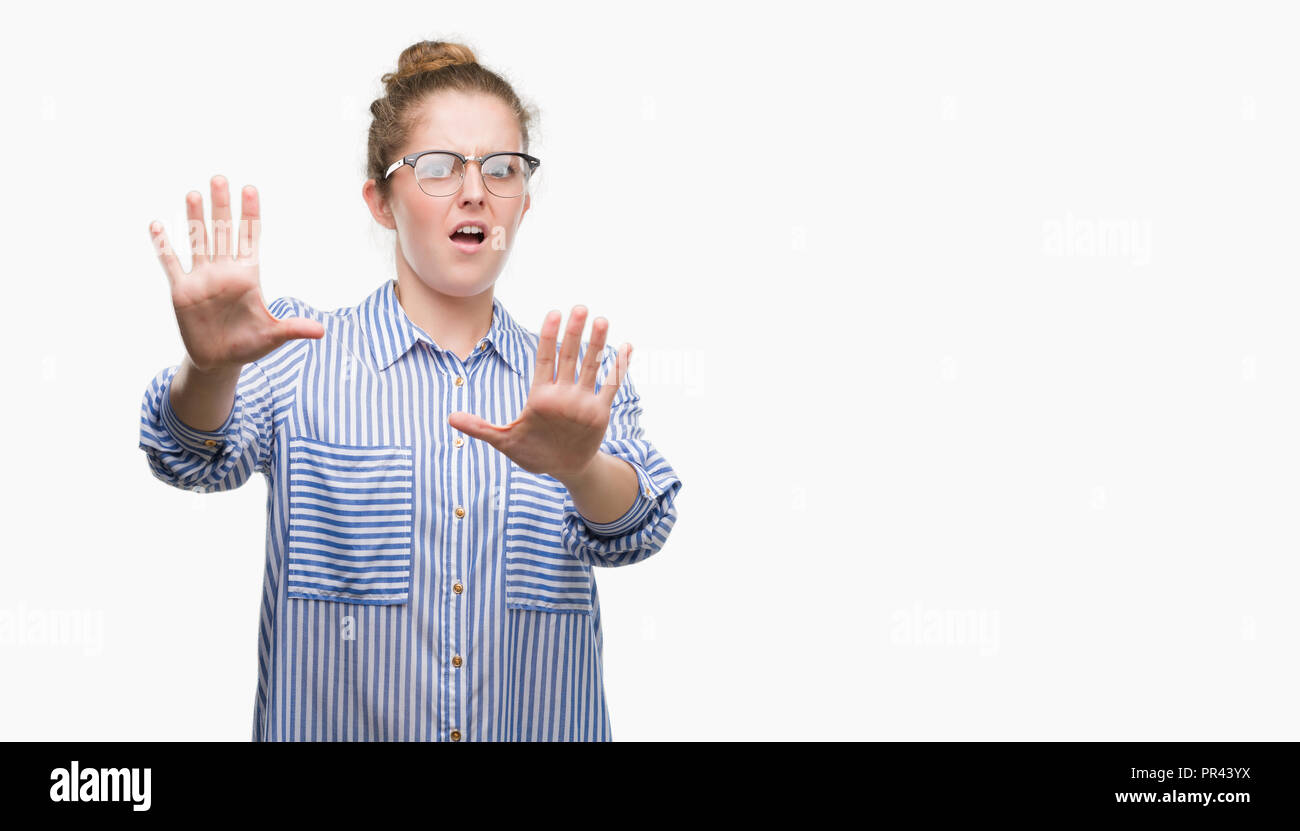 Young blonde business woman afraid and terrified with fear expression ...