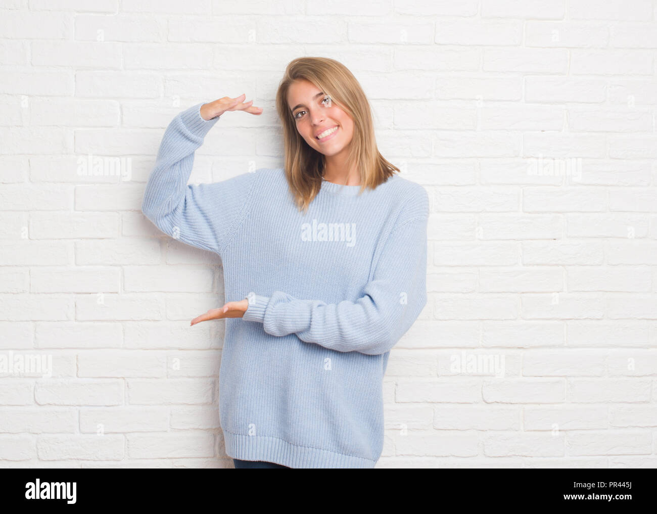 Beautiful young woman over white brick wall gesturing with hands ...