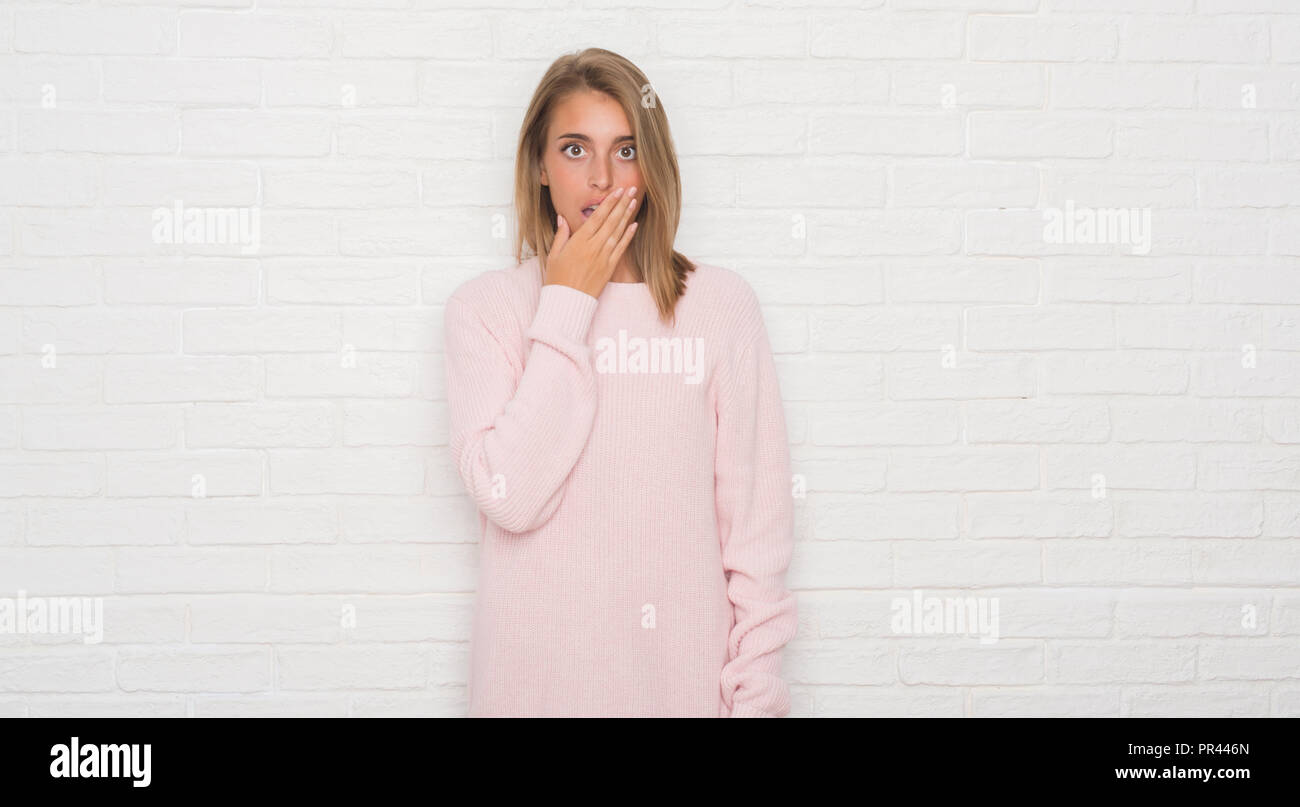 Beautiful young woman over white brick wall cover mouth with hand ...