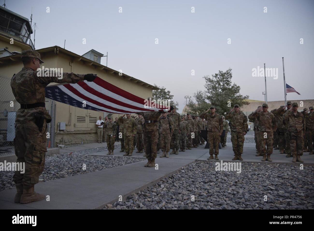 Servicemembers salute as the Bagram Airfield Base Honor Guard folds a ...