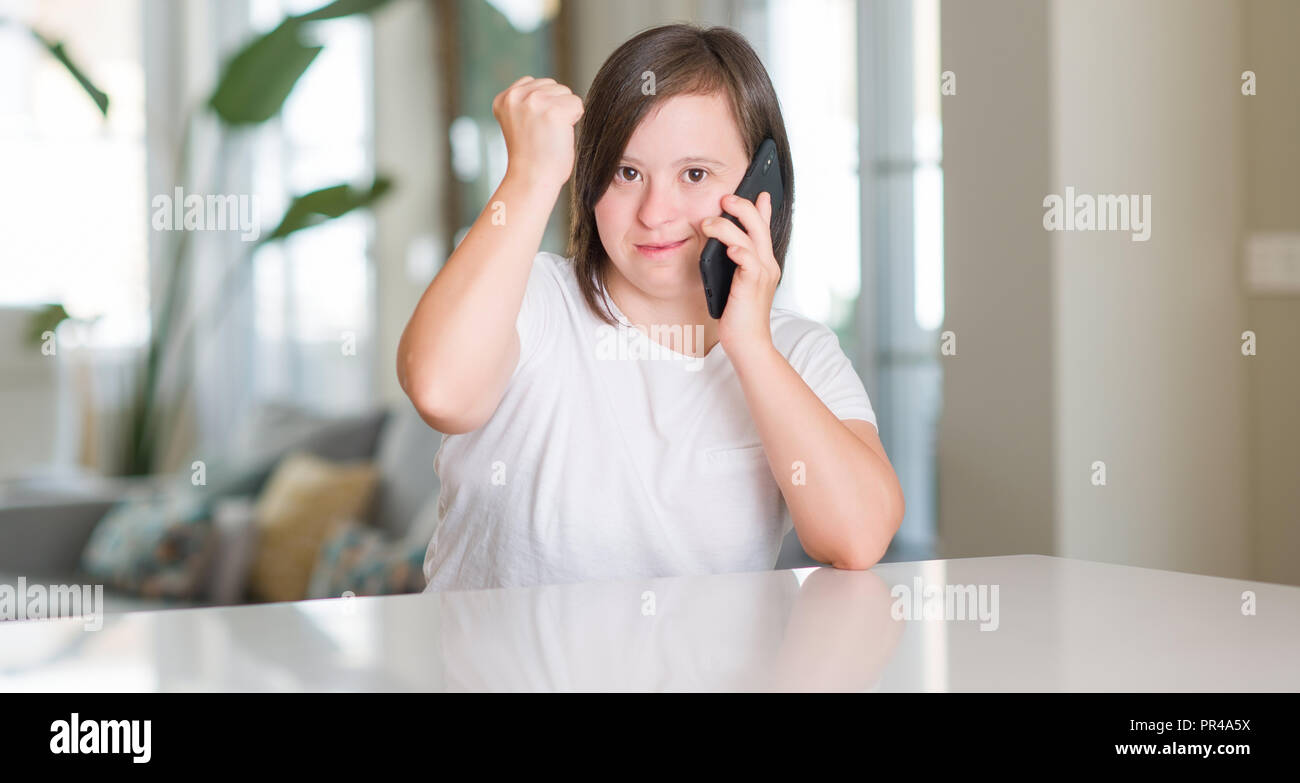 Down syndrome woman at home using smartphone annoyed and frustrated ...
