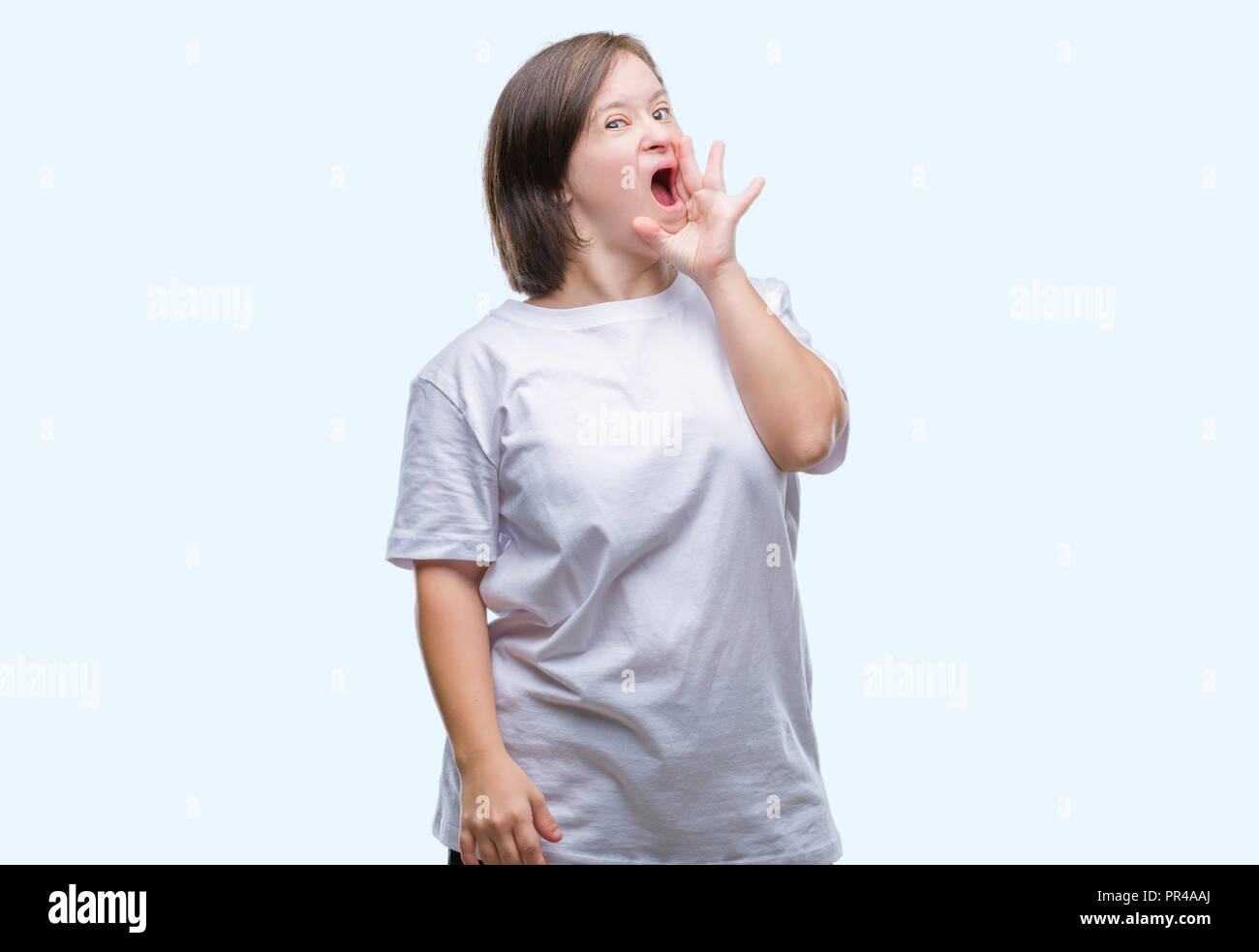 Young adult woman with down syndrome over isolated background shouting ...