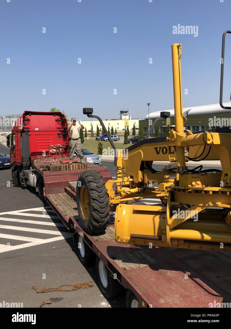 An Airman guides a grading vehicle onto the bed of a truck to prepare ...