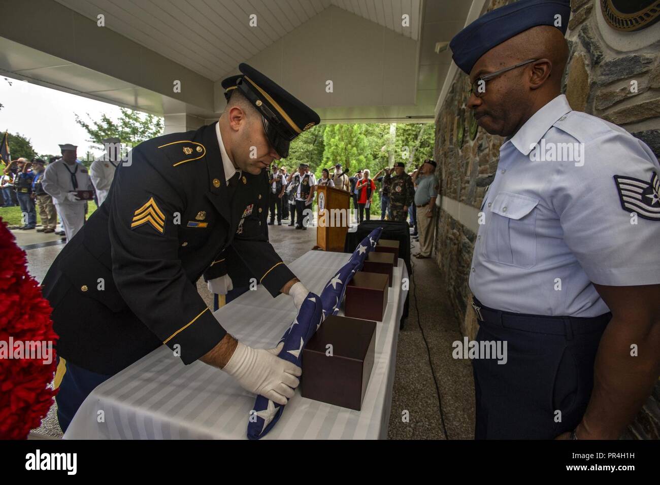 U.S. Army Sgt. Mike DeMayo, left, places a flag in front of an urn ...