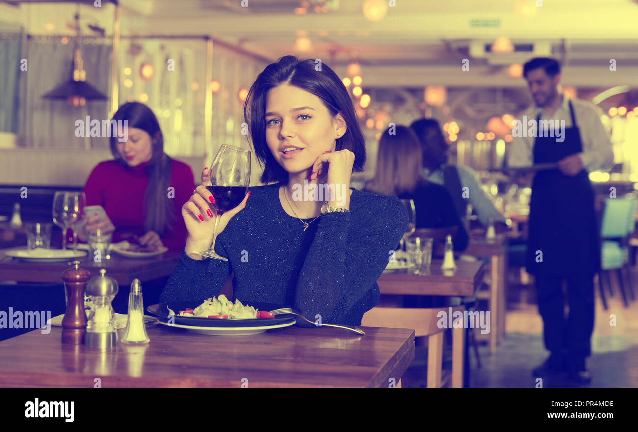 Portrait of elegant young lady with glass of wine, tasting delicious ...