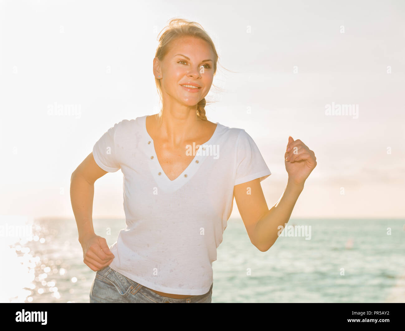 Sportswoman is jogging on the beach near the ocean Stock Photo - Alamy
