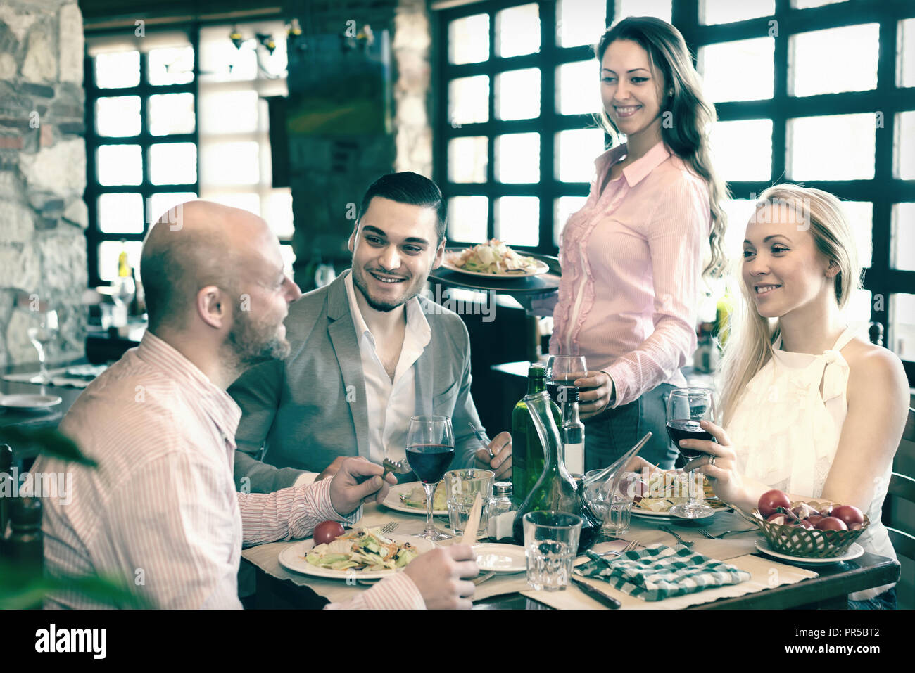 Portrait of cheerful adults people having dinner and respectful waiter ...