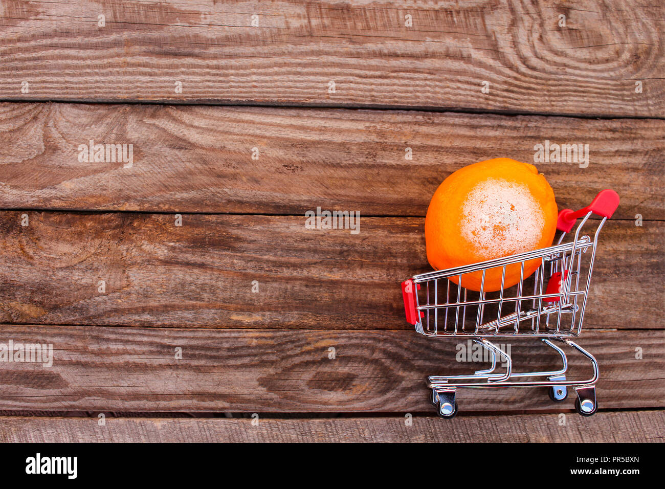 Shopping cart with rotten orange on the old wood background. Mold on ...