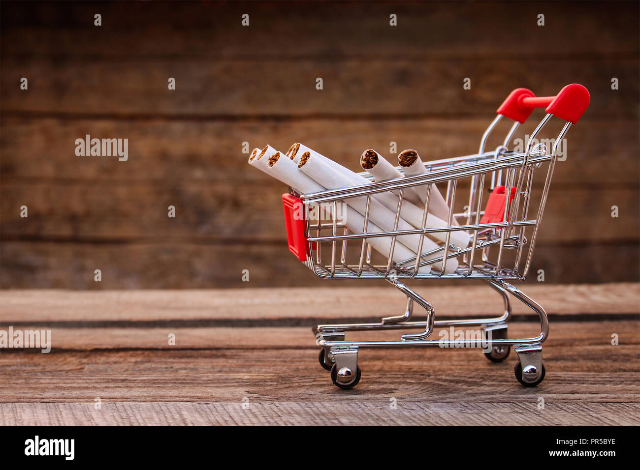 Shopping cart with cigarette on the old wood background. Toned image ...