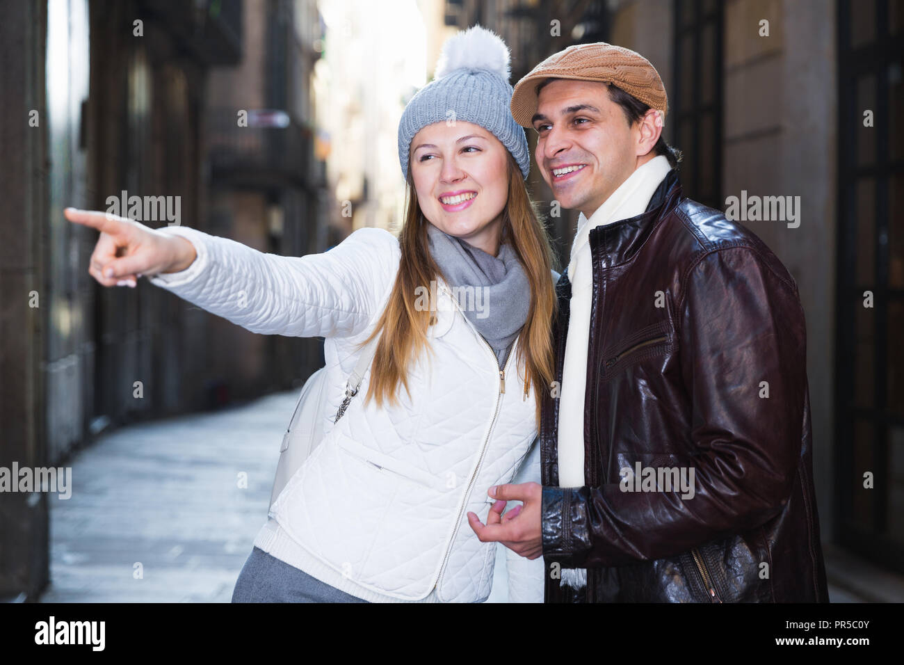 Adult tourists in hats and scarfs pointing finger on historical object ...