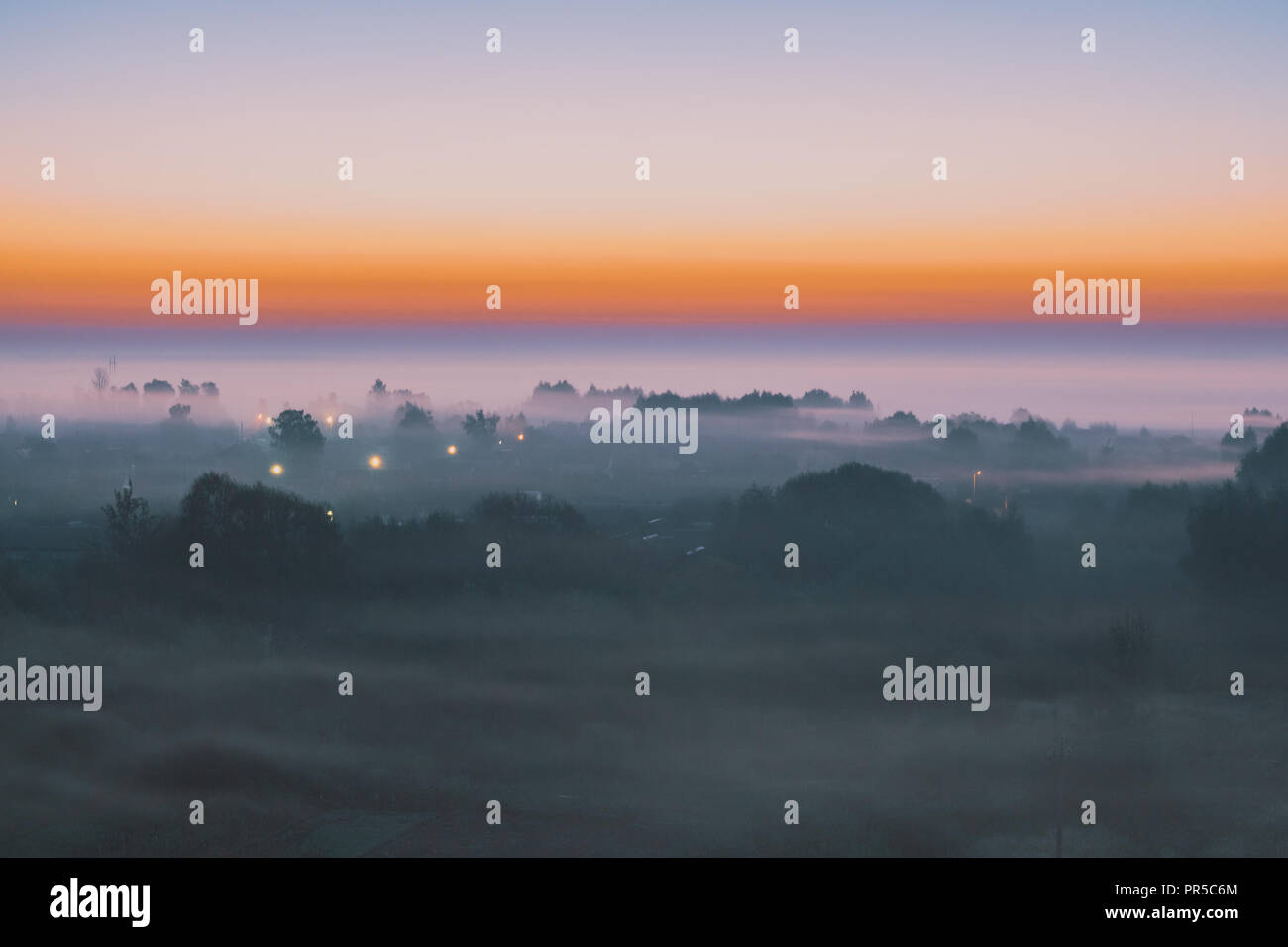 Dawn in the fog over a small village among a small forest. Top view ...