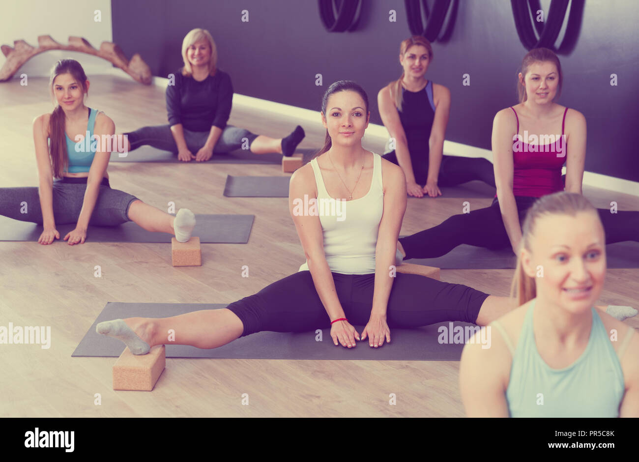Young women exercising yoga poses in fitness center Stock Photo - Alamy