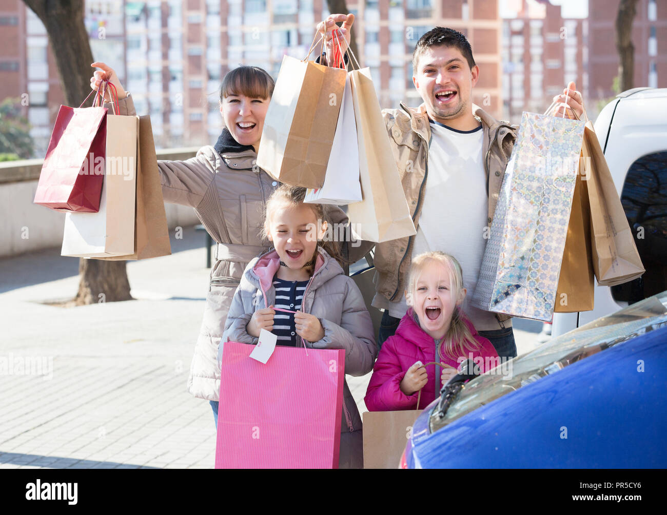 Happy parents with two girls holding shopping bags in sunny day Stock ...