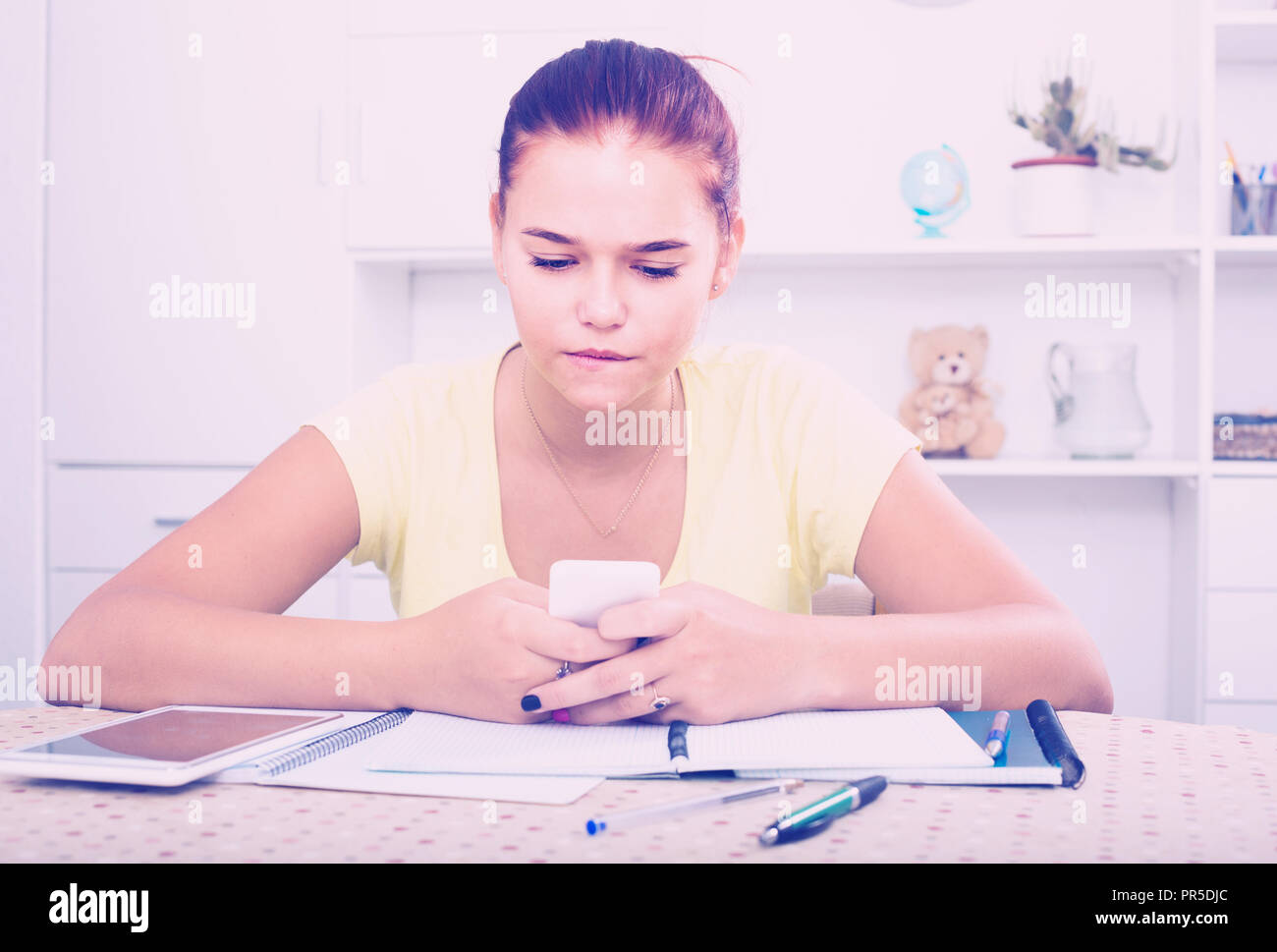 Young smiling american teenage girl sitting and typing message on her ...
